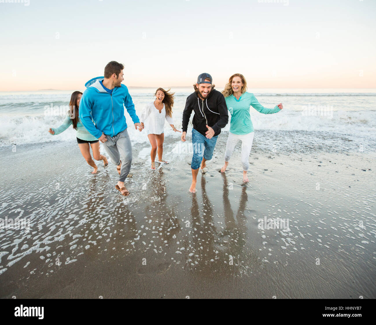 Smiling friends running on beach Stock Photo - Alamy
