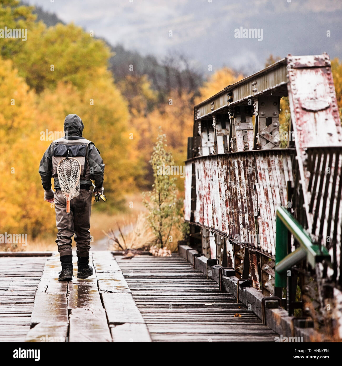 Caucasian man carrying fishing rod on bridge Stock Photo - Alamy