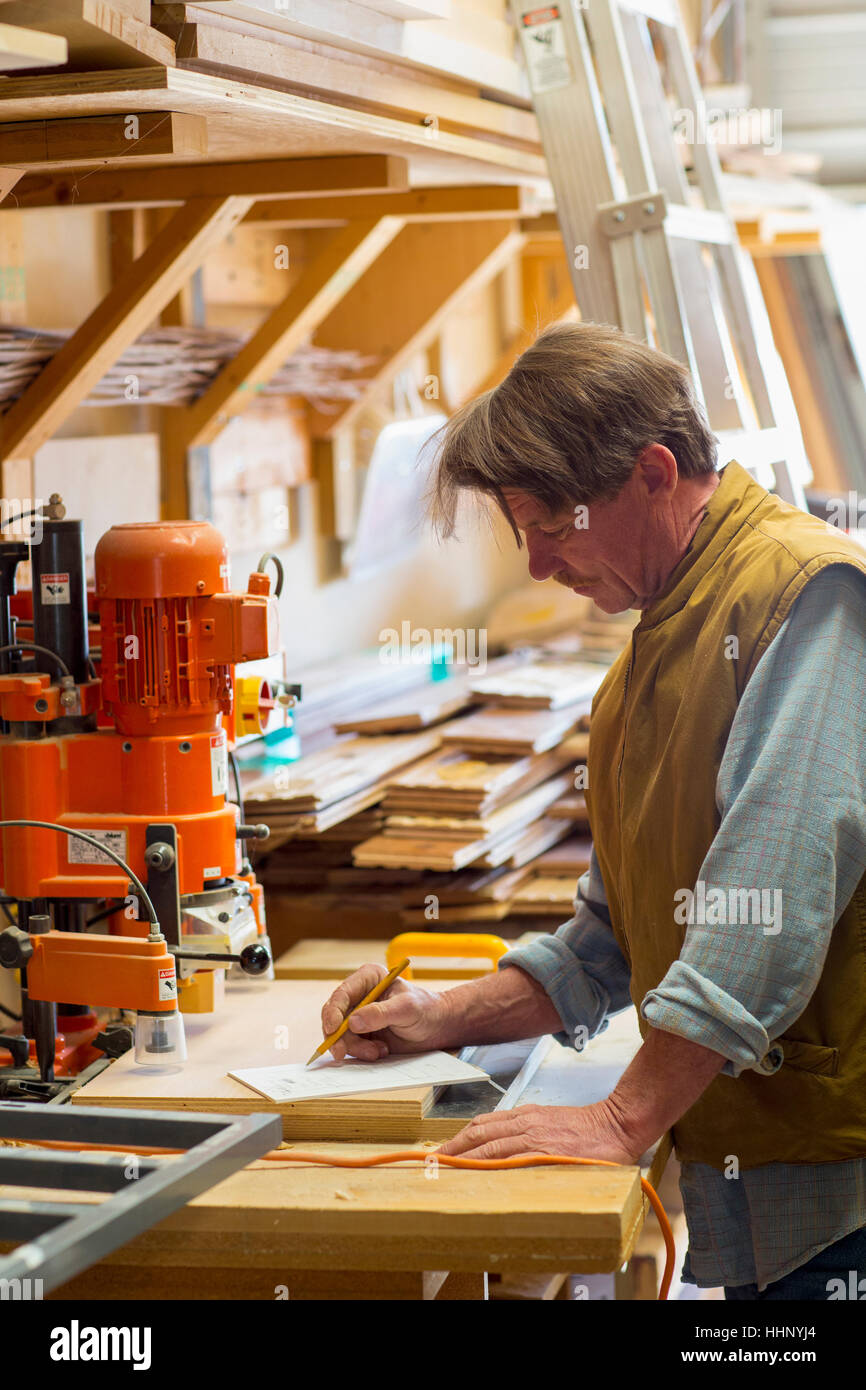 Caucasian carpenter writing on notepad in workshop Stock Photo - Alamy