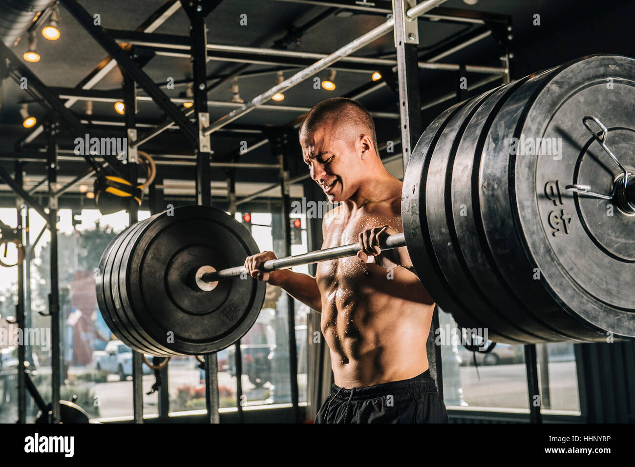Man lifting heavy barbell in gymnasium Stock Photo - Alamy