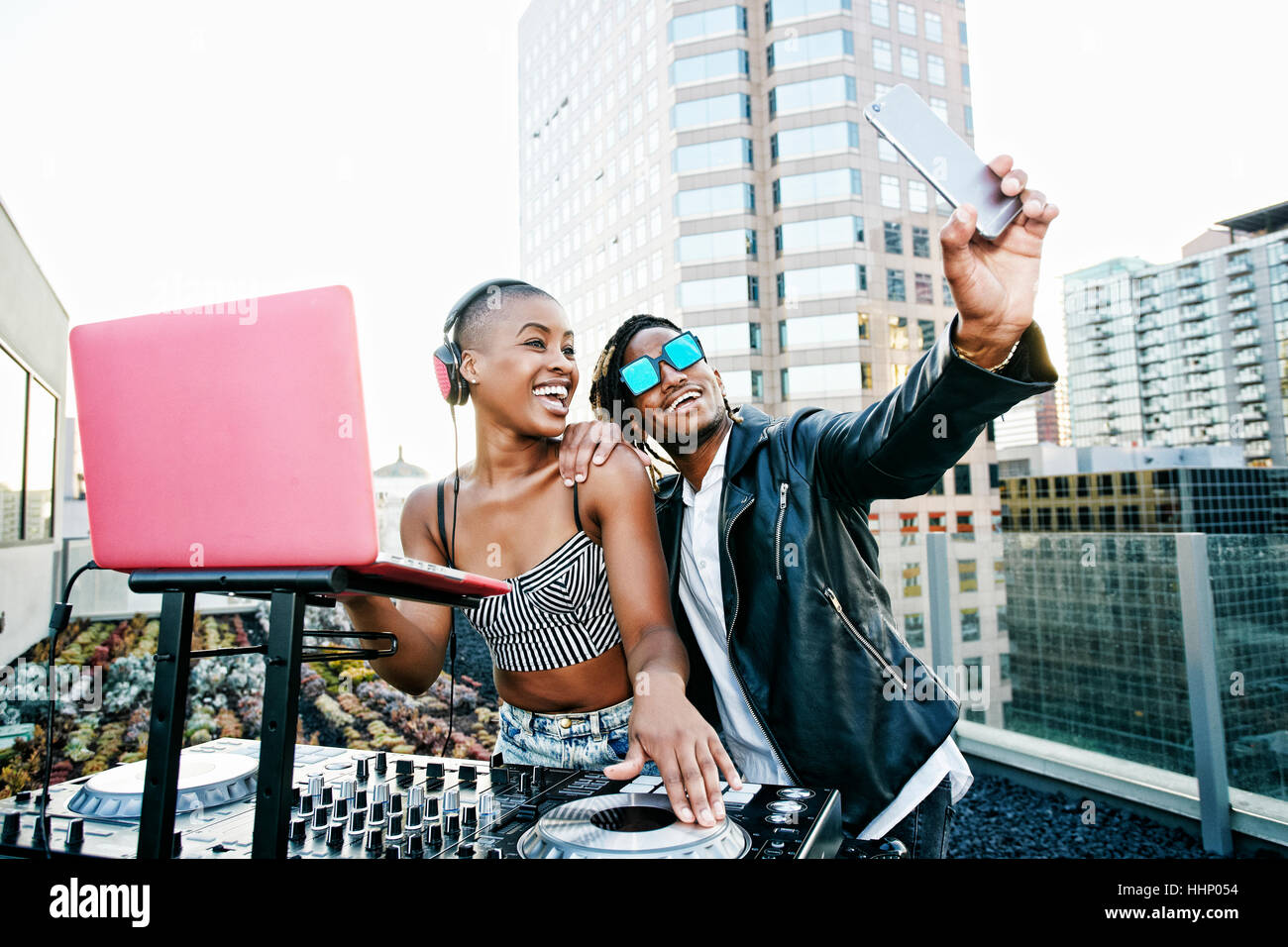 Black DJ and man posing for cell phone selfie on urban rooftop Stock ...