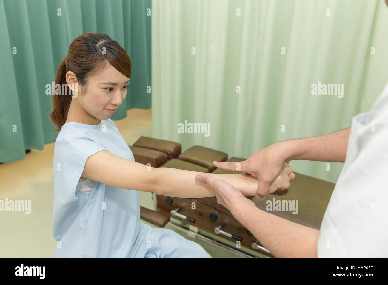 Doctor Manipulating the Arms of A Woman Stock Photo - Alamy