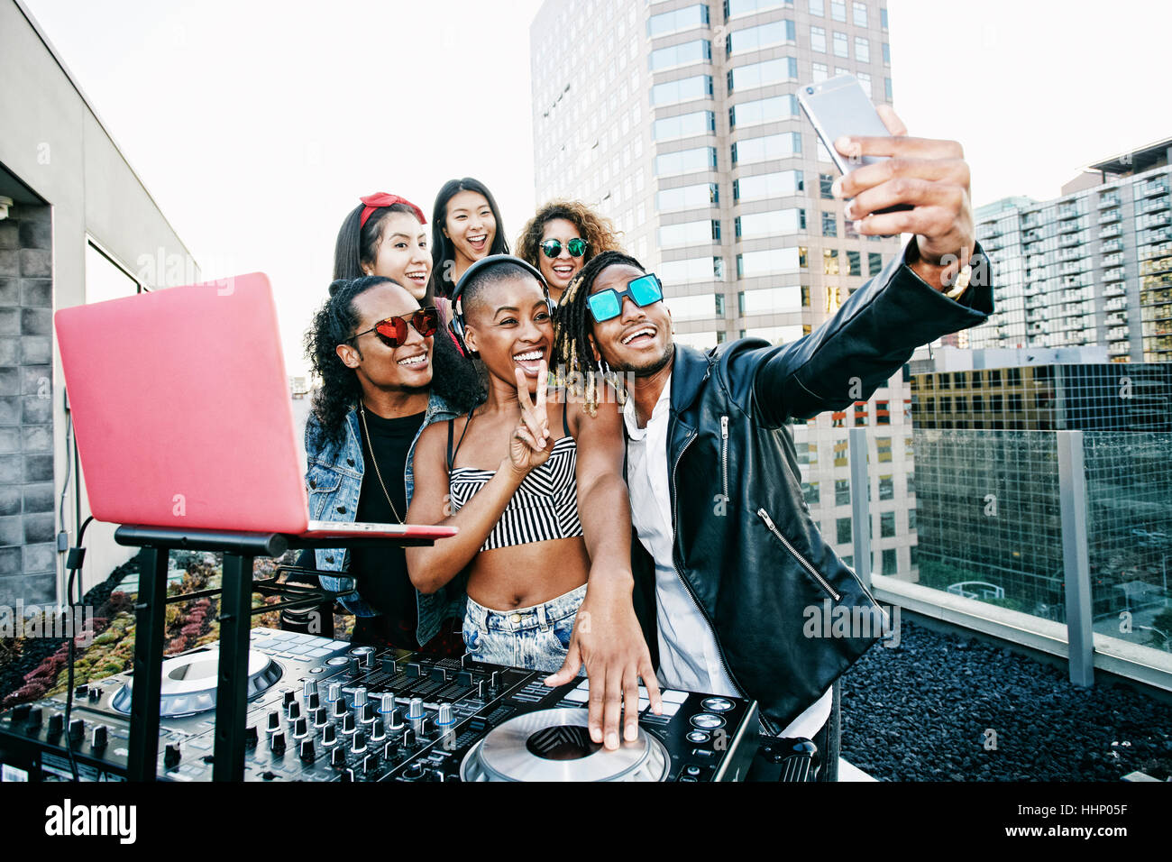 Friends posing for cell phone selfie with DJ on urban rooftop Stock ...