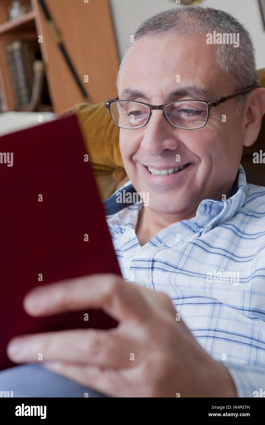 Smiling Hispanic man reading book Stock Photo - Alamy