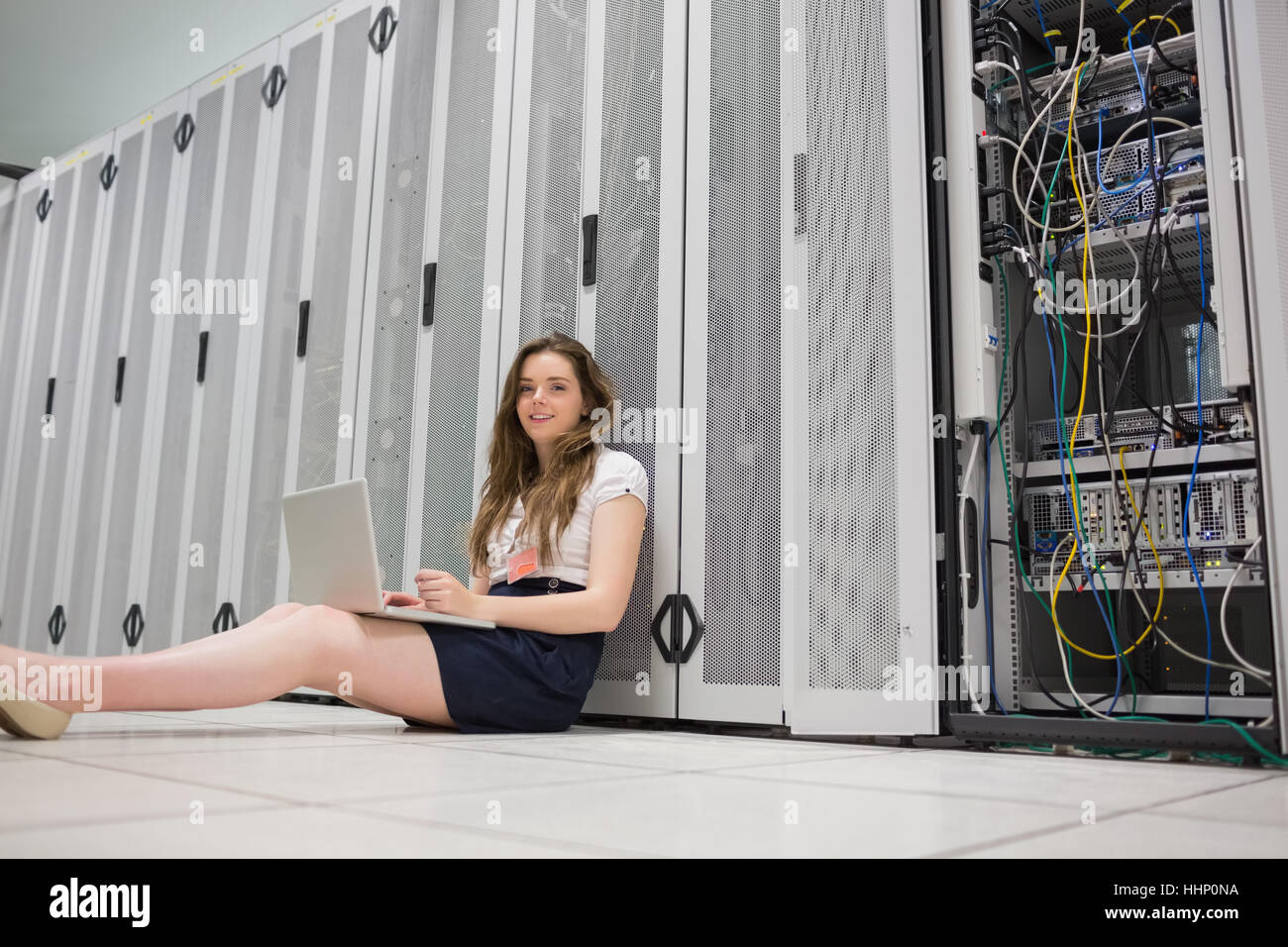 Happy woman sitting on floor working on laptop in data center Stock ...