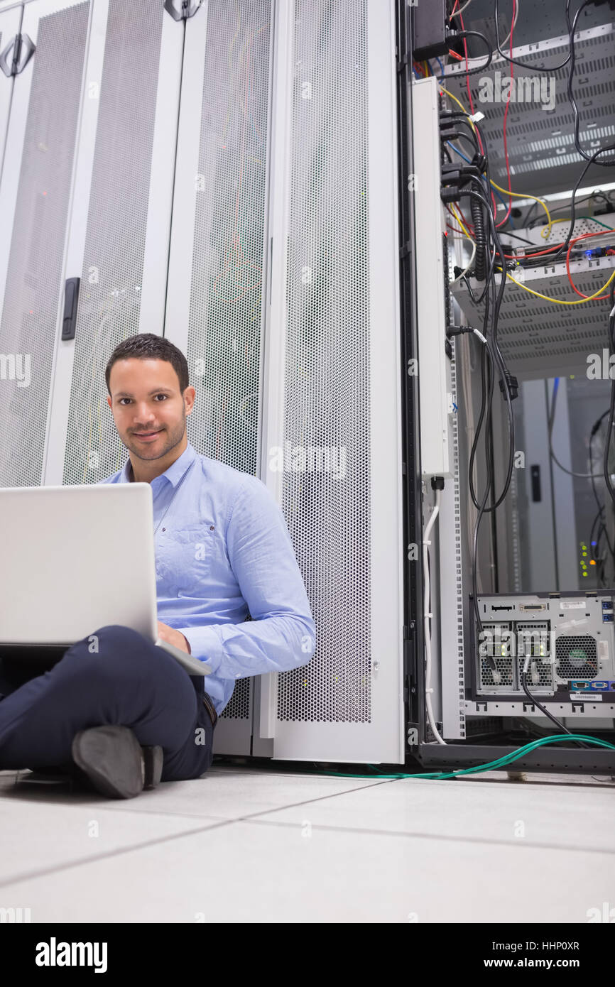 Man sitting on floor using laptop to check servers in data center Stock ...