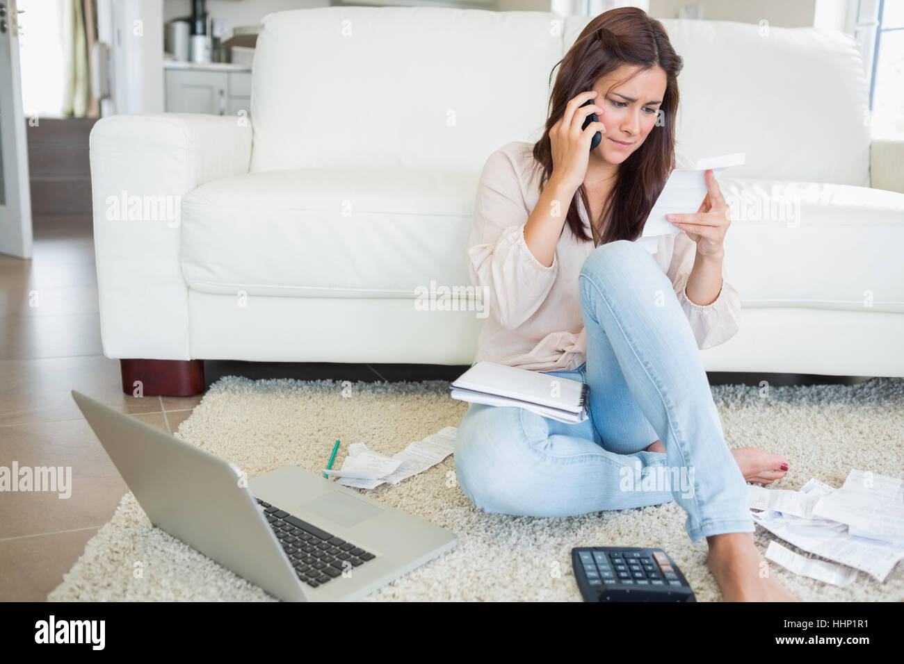 Woman calling and reading a bill on floor of living room Stock Photo ...