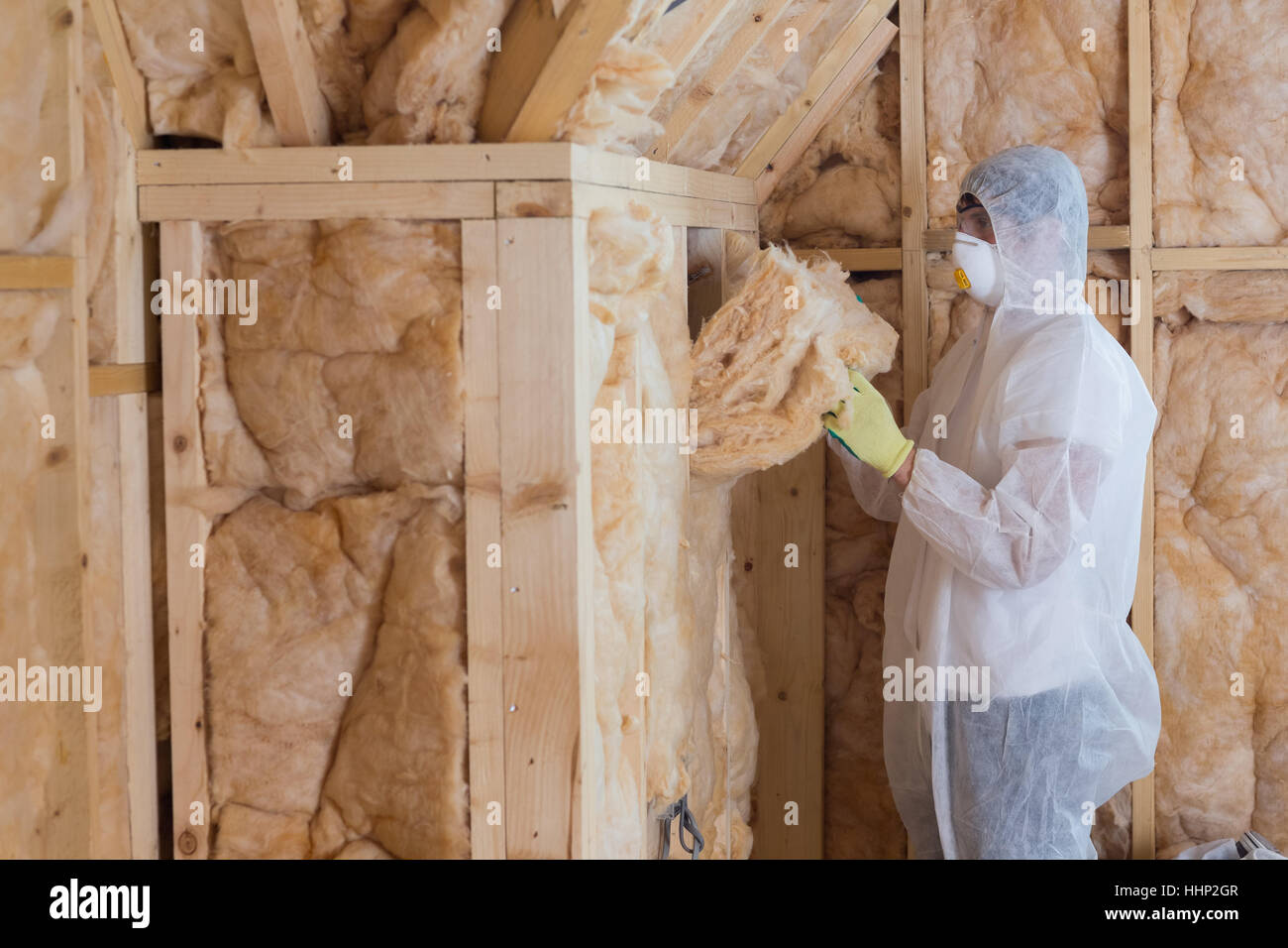 Worker filling walls with insulation material in construction site ...