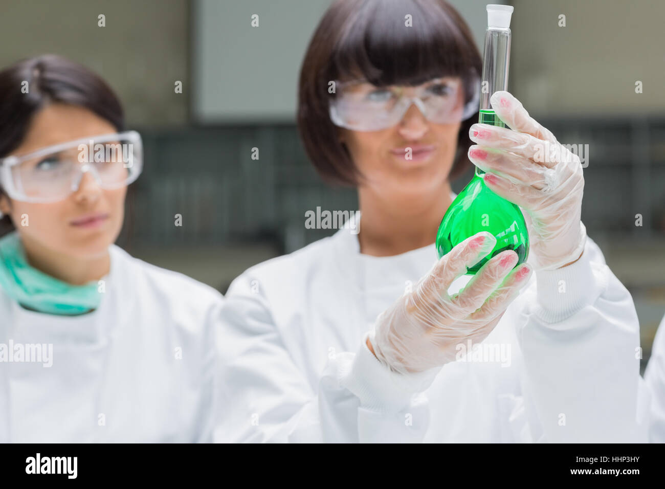 Female chemists viewing t green liquid in the laboratory Stock Photo ...