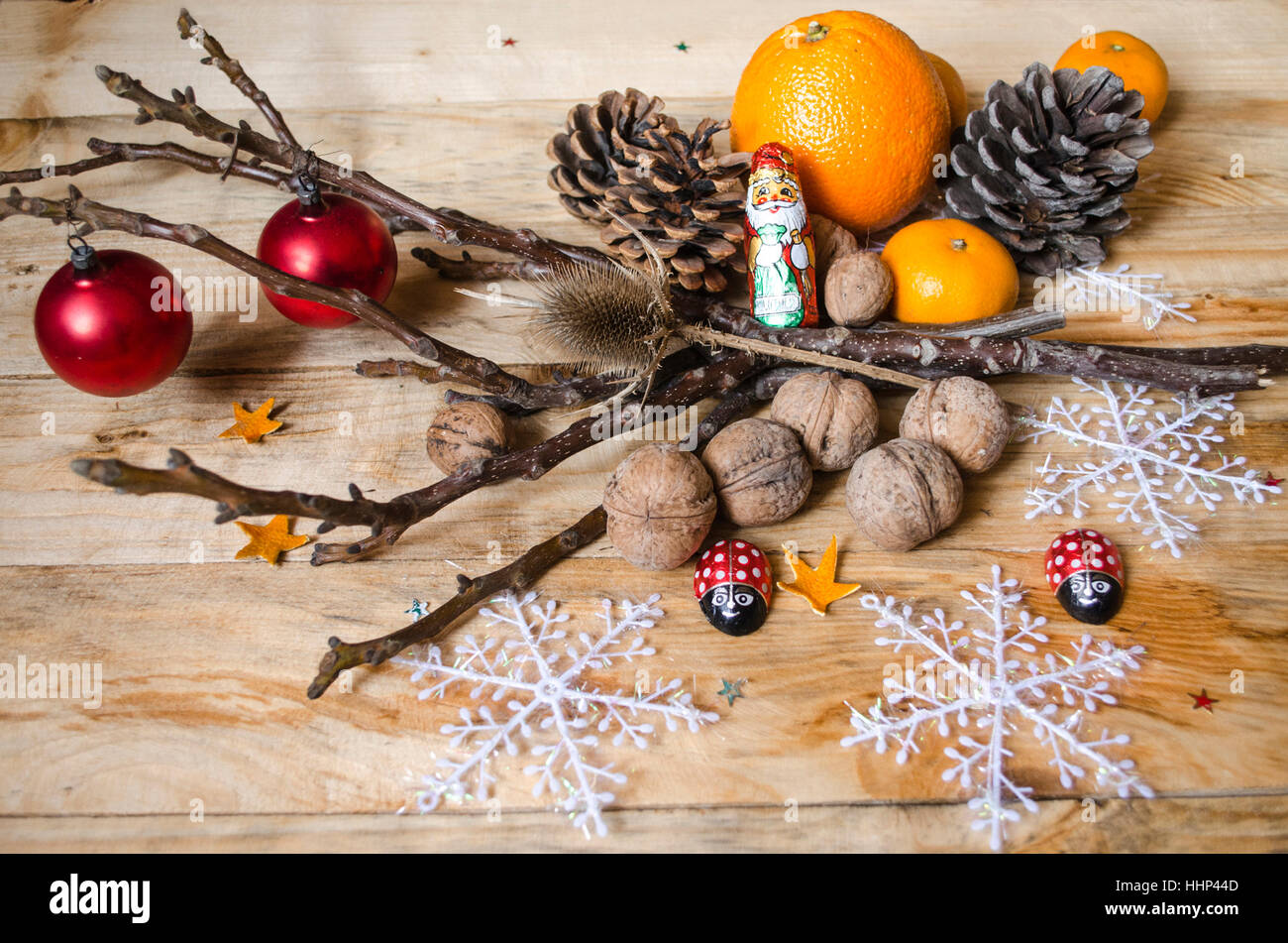 Citrus fruits, chocolate Santa, nuts with cones and toys on boards ...