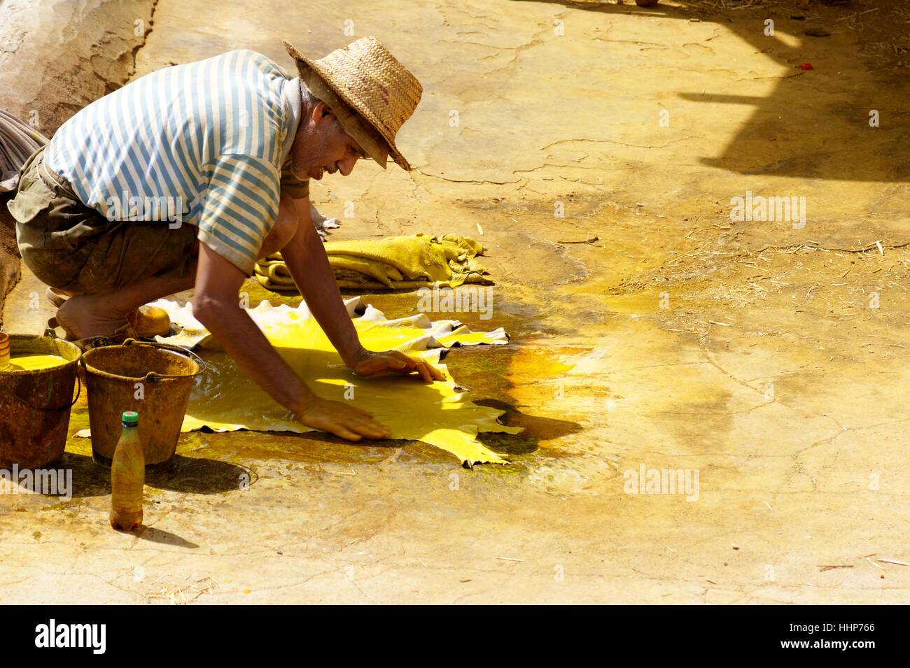Male working yellow dye into rawhide inside the historic tannery ...