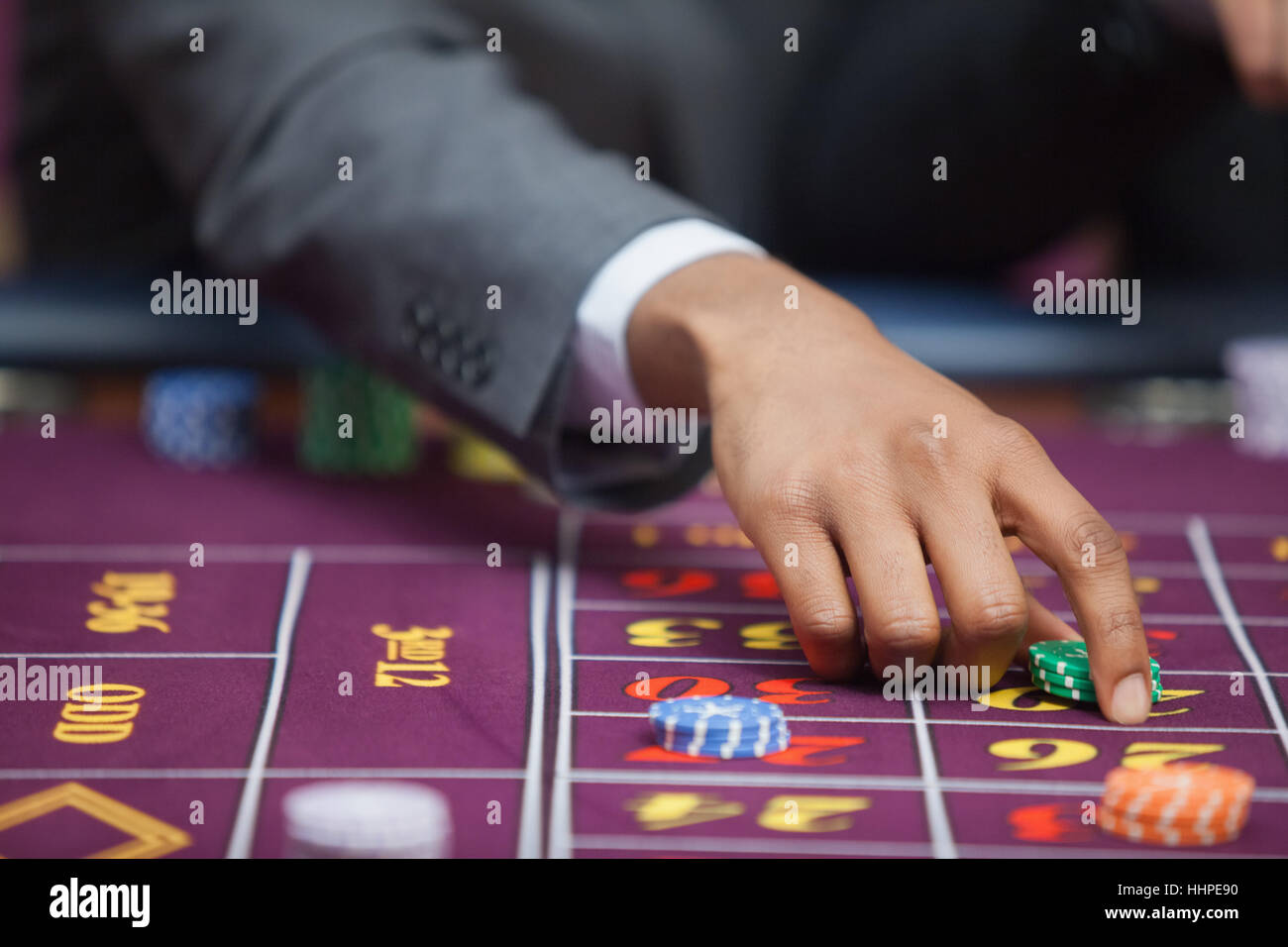 Man in a casino is placing a bet at roulette table Stock Photo - Alamy