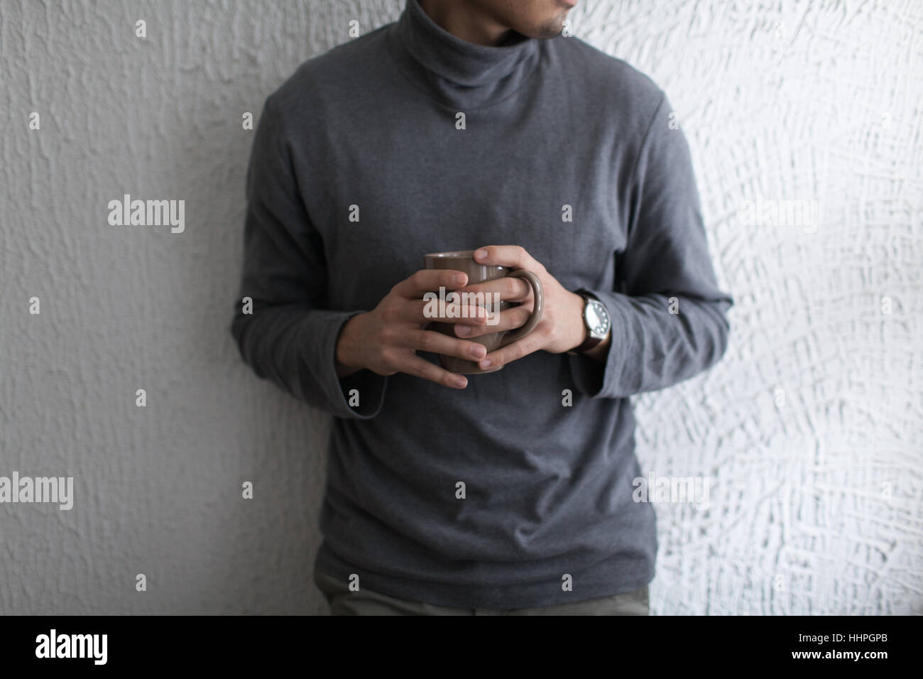 Filipino man standing against a wall holding a mug Stock Photo - Alamy