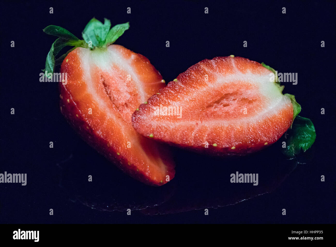 Single sliced strawberry on black Stock Photo - Alamy