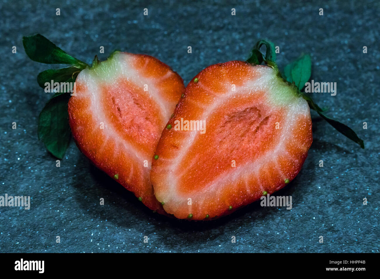Single sliced strawberry on gray stone Stock Photo - Alamy