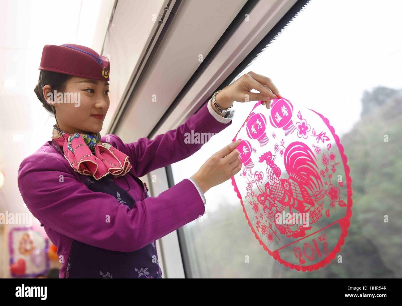 Chengdu. 20th Jan, 2017. A railway stewardess pastes window decoration ...