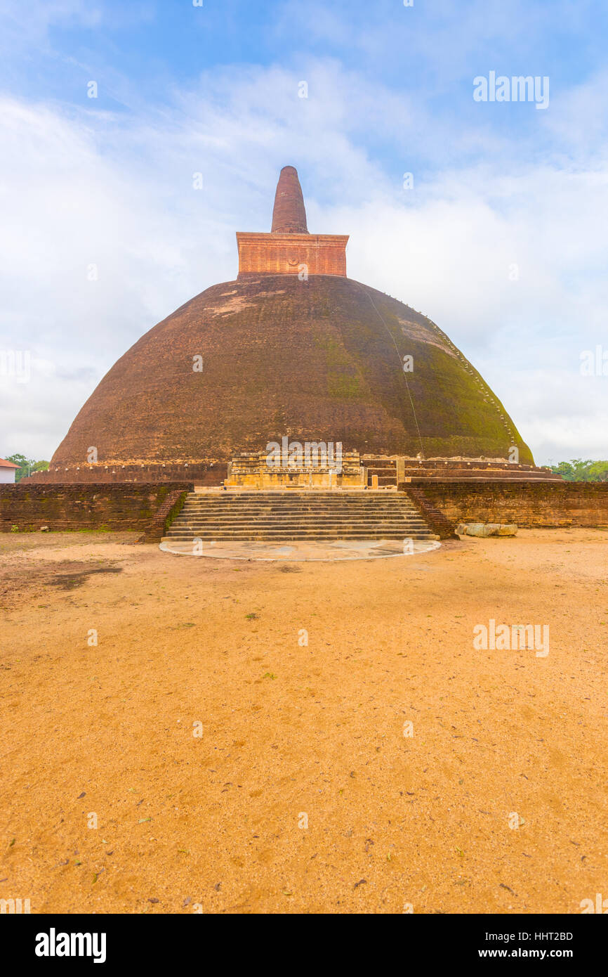 Dirt field foreground leading to steps of Abhayagiri Stupa ruins on a ...