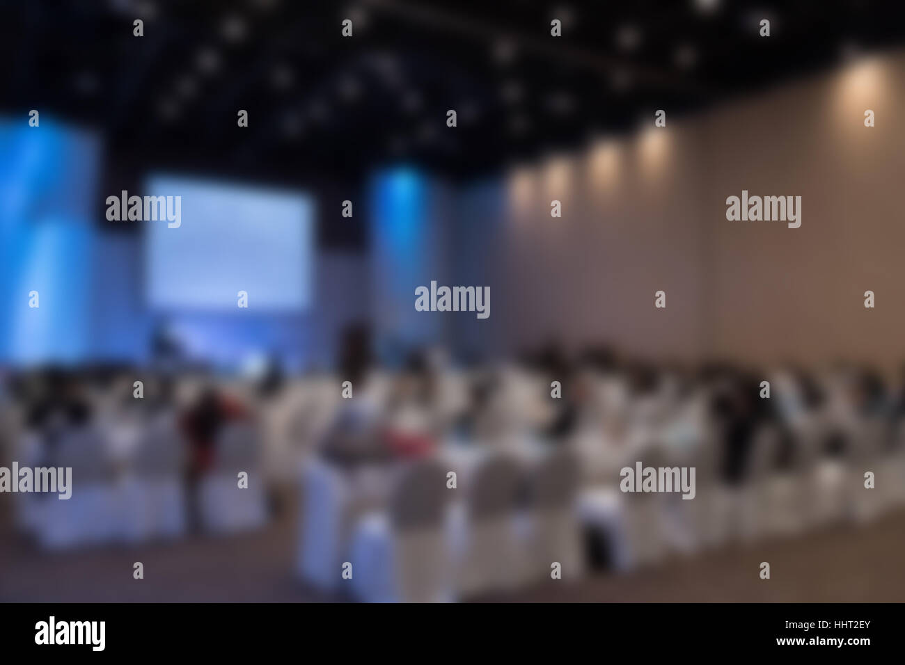 people sit on rows of chairs in large conference convention hall during ...