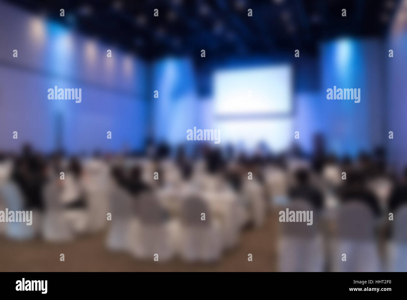 people sit on rows of chairs in large conference convention hall during ...