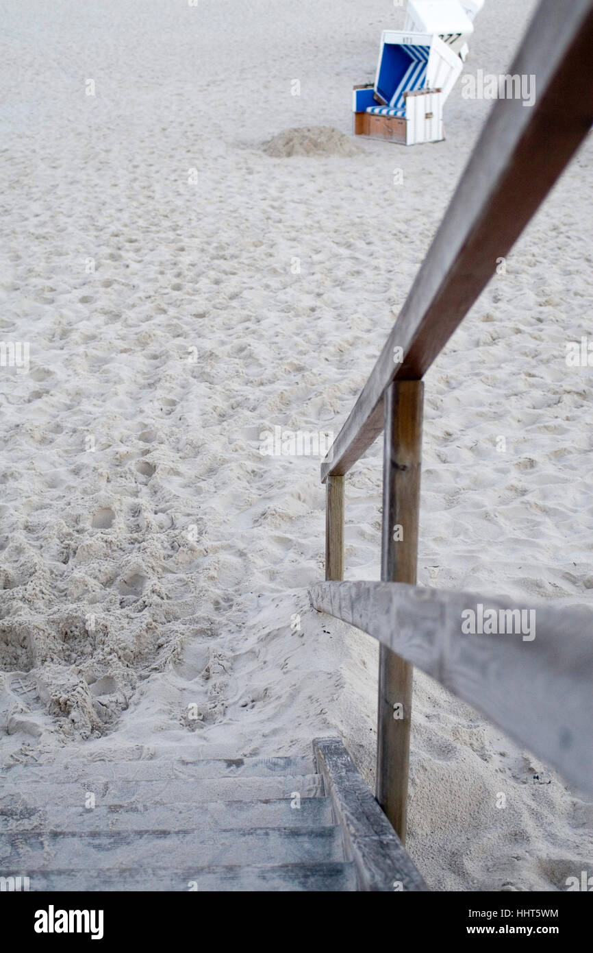 wooden staircase with railings leading to the beach and beach chairs ...