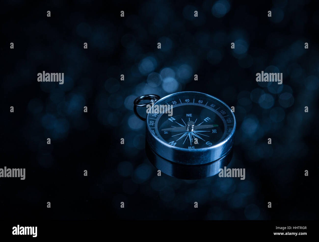 Classic compass on dark blue illuminated background Stock Photo - Alamy