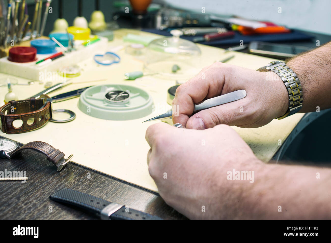 In a clock repair shop. Table with various precise equipment and hands ...