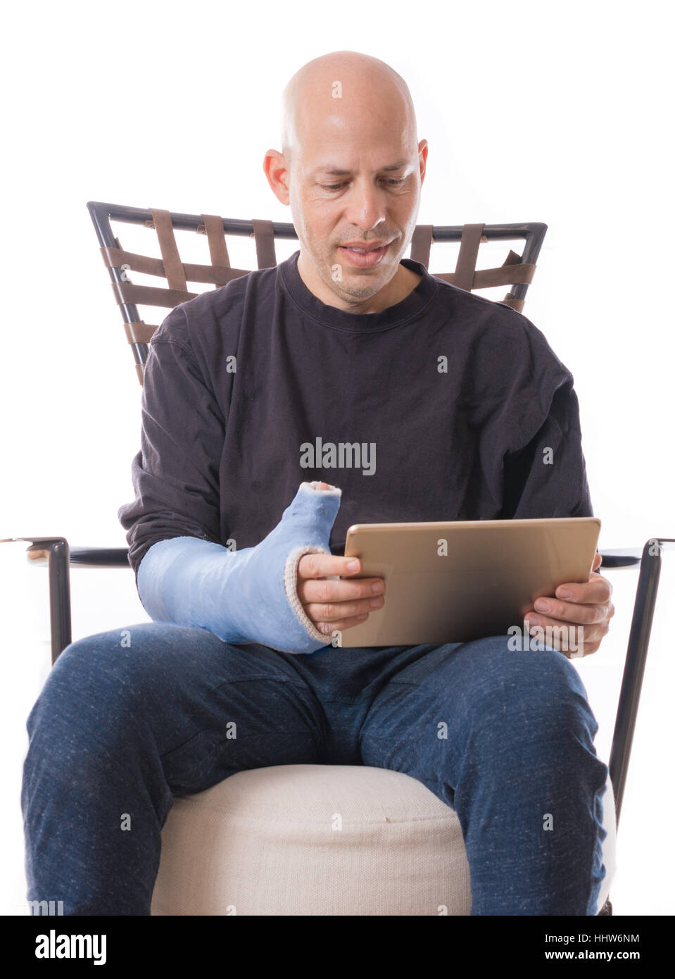 Young man with a cast on his arm using a handicapped accessible tablet ...