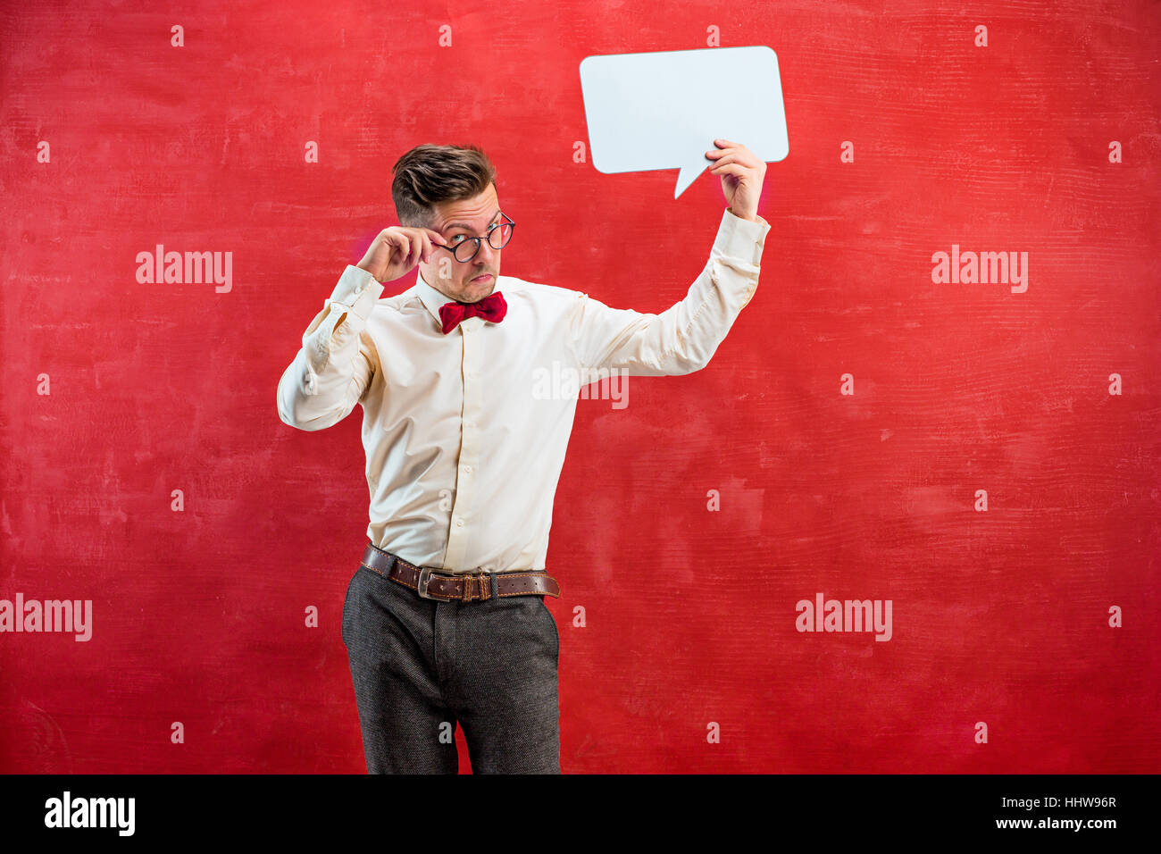 Young disappointed funny man with empty blank sign on red studio ...