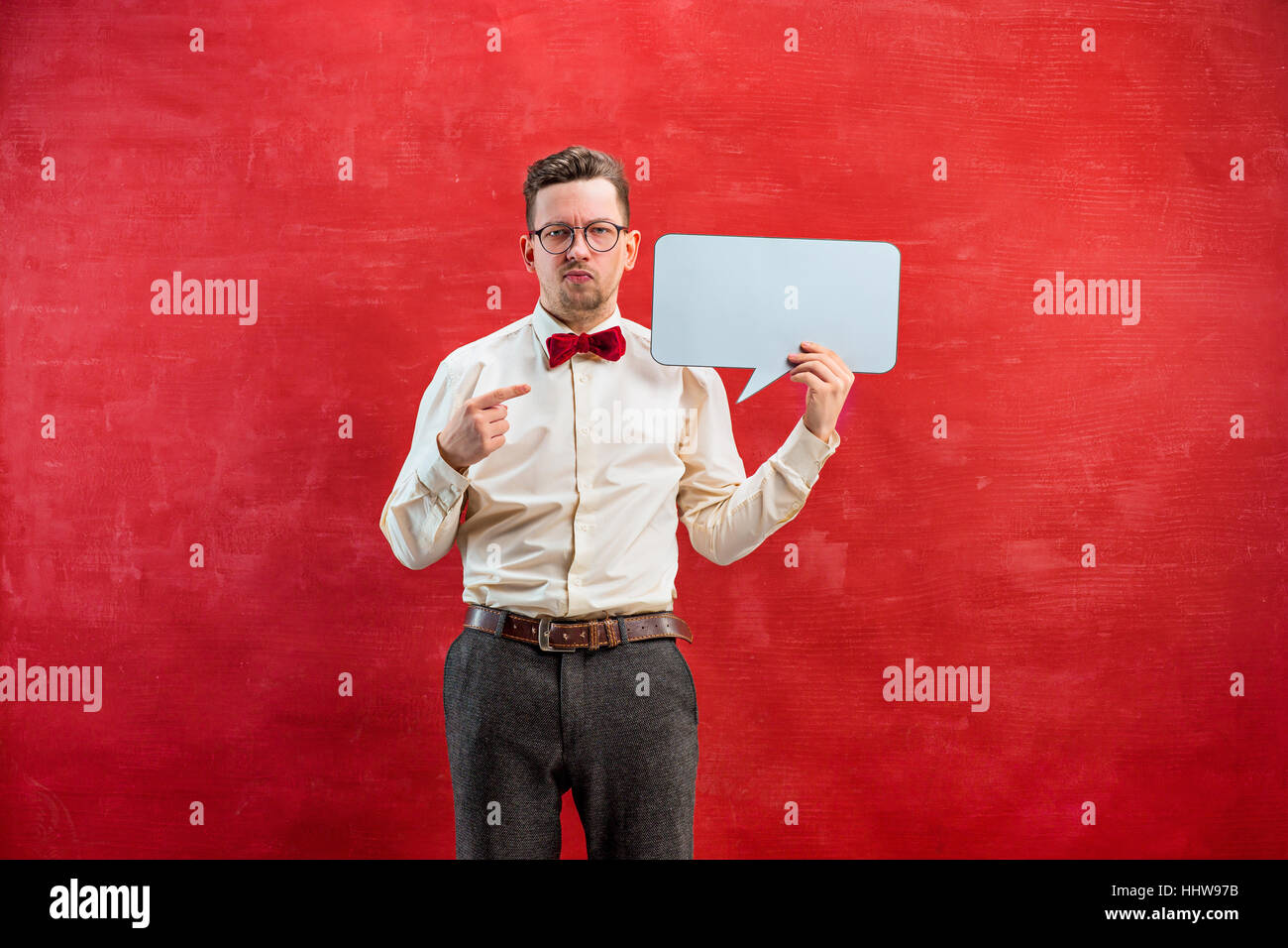 Young disappointed funny man with empty blank sign on red studio ...
