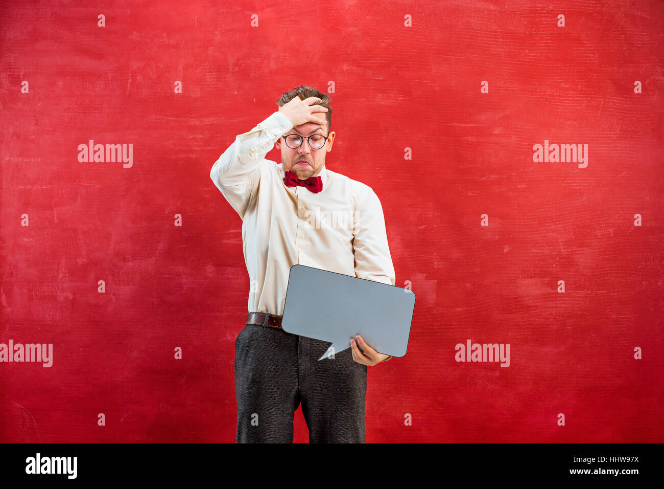 Young disappointed funny man with empty blank sign on red studio ...