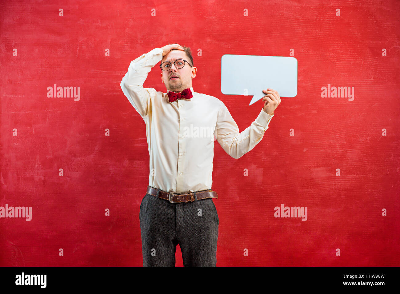 Young disappointed funny man with empty blank sign on red studio ...