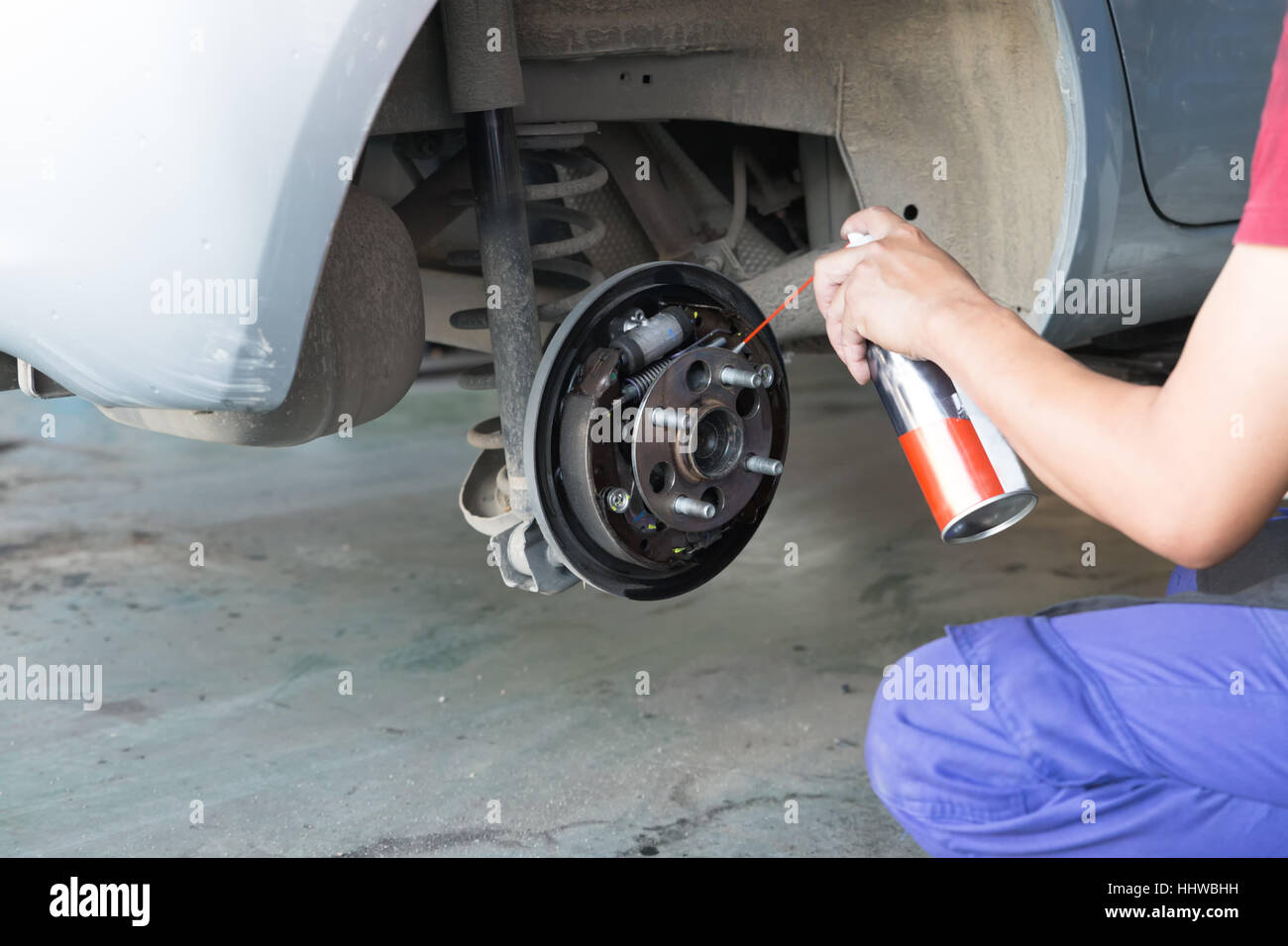 mechanic spray chemical to clean brake during tyre replacement service ...