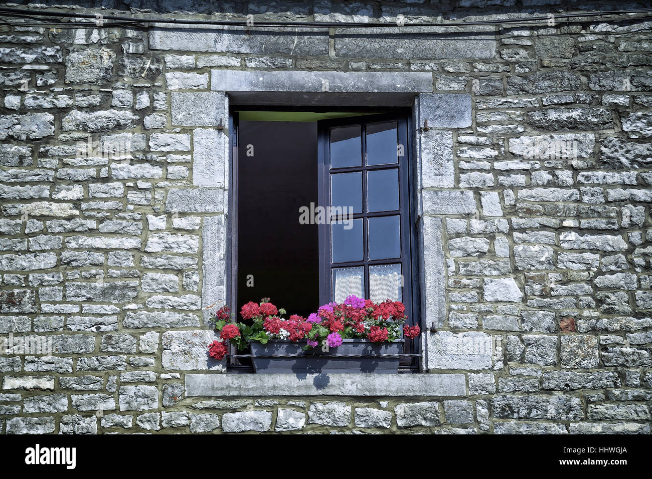 Open window with red flowers in traditional european village house ...