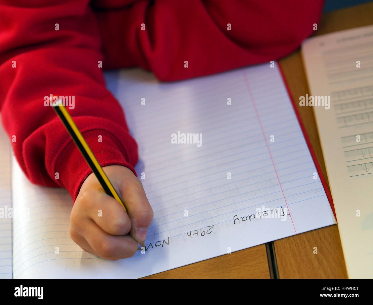 primary school child writing in an exercise book Stock Photo - Alamy