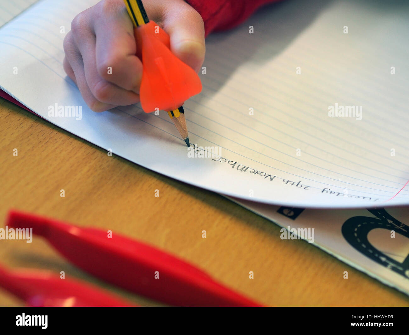 primary school child writing in exercise book and learning to hold ...