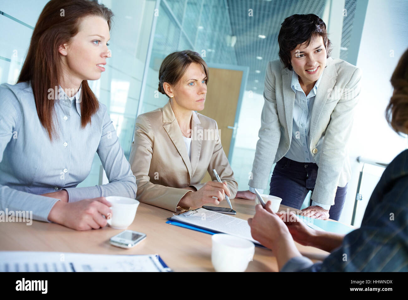 Image of three attentive businesswomen listening to their employer at ...