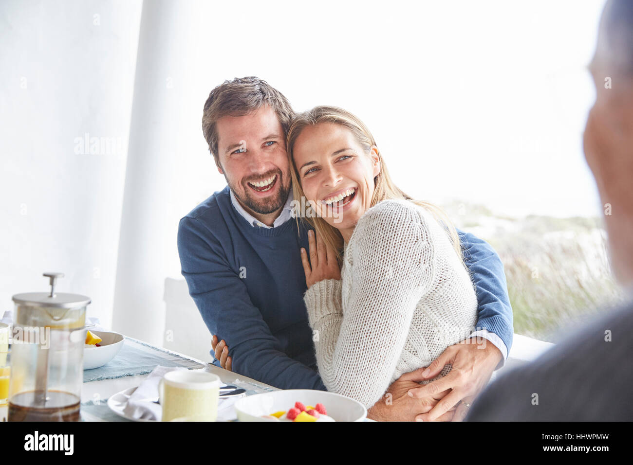 Happy affectionate couple laughing and hugging at patio breakfast Stock ...