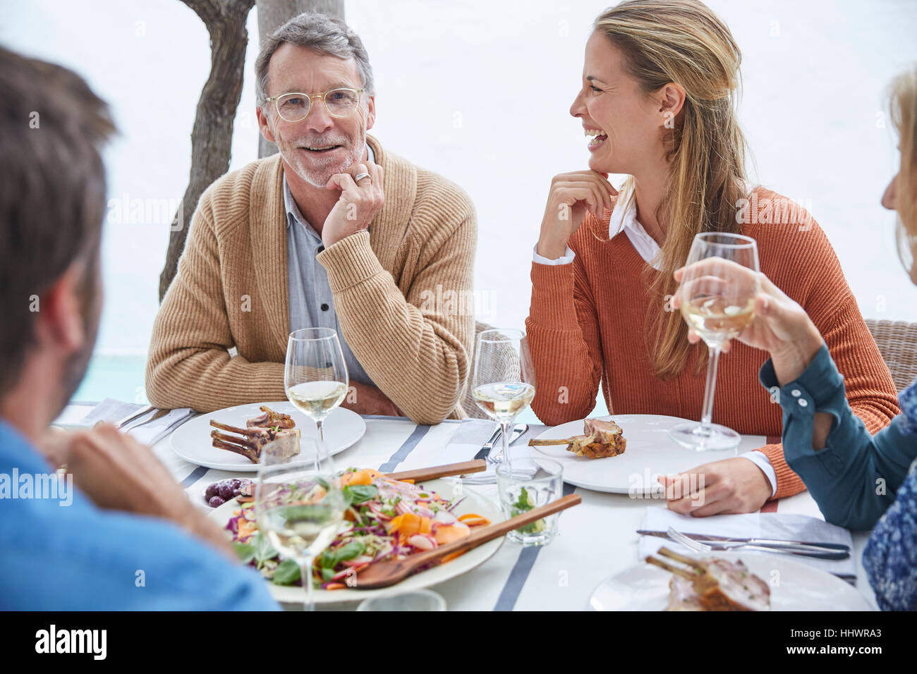 Couples drinking white wine and eating lunch at patio table Stock Photo ...