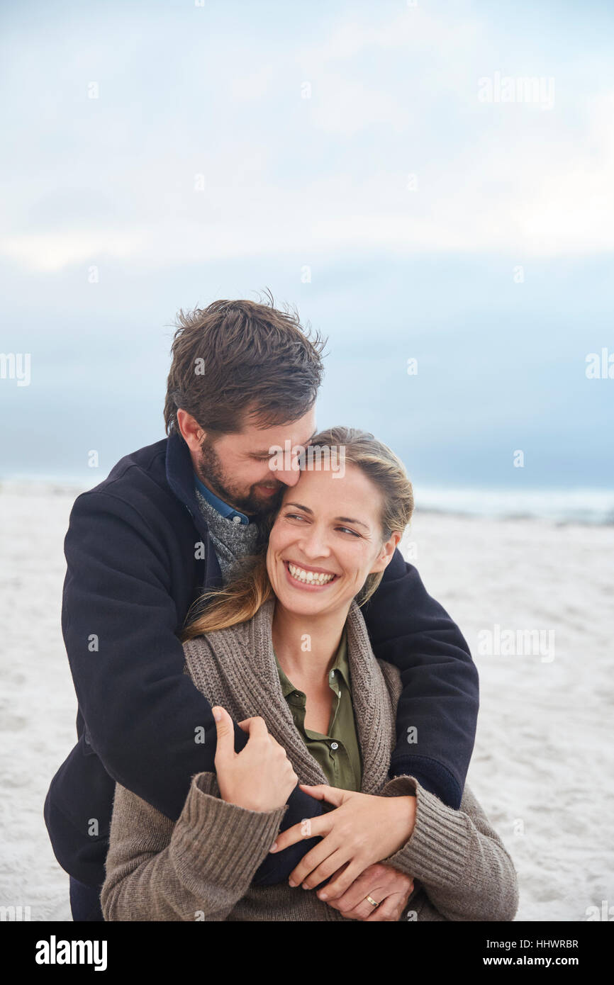 Smiling affectionate couple hugging on winter beach Stock Photo - Alamy
