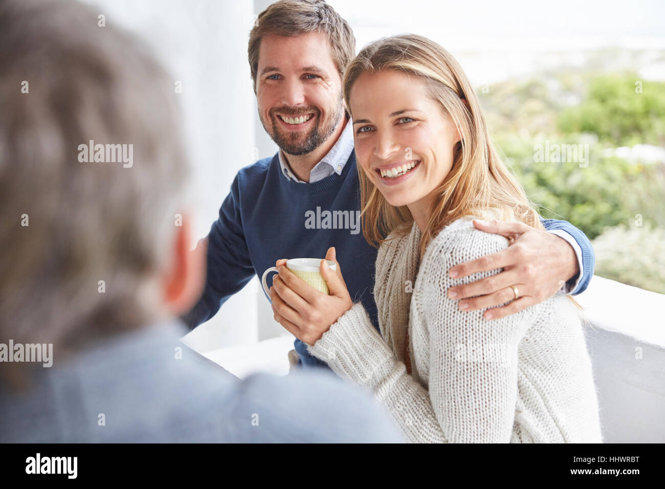 Smiling affectionate couple hugging and drinking coffee on patio Stock ...