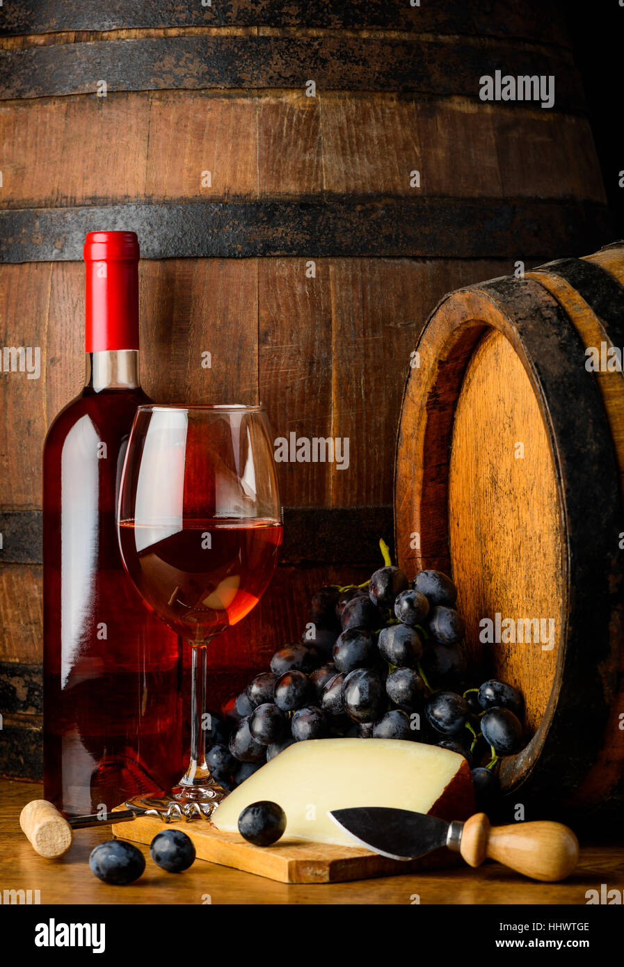 Rose wine bootle and glass, cheese and grapes in still life on wooden ...
