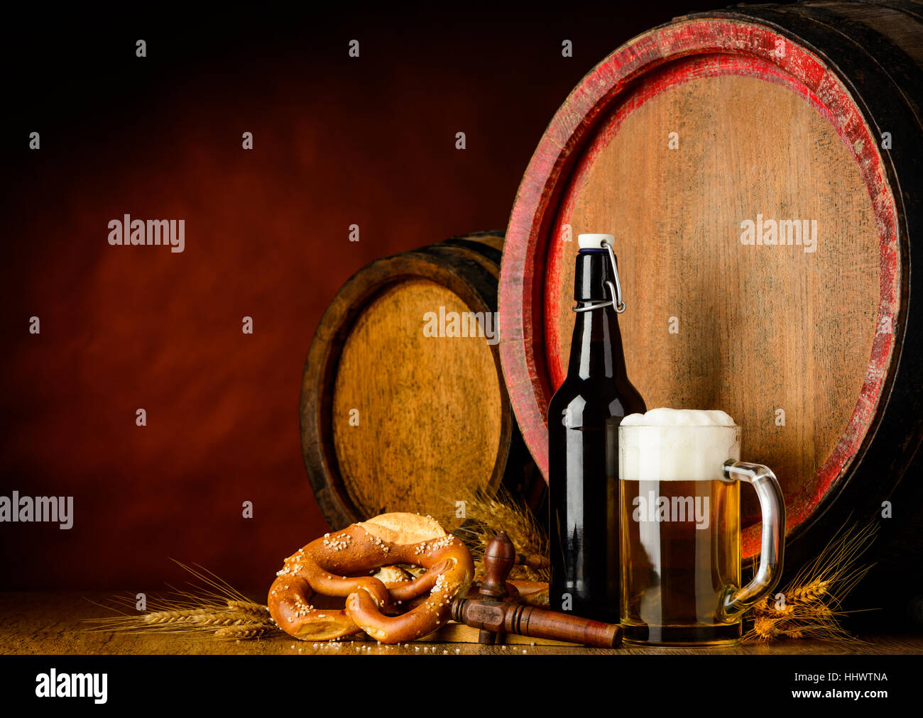 Beer bottle and glass with barel on dark background with brezel and ...