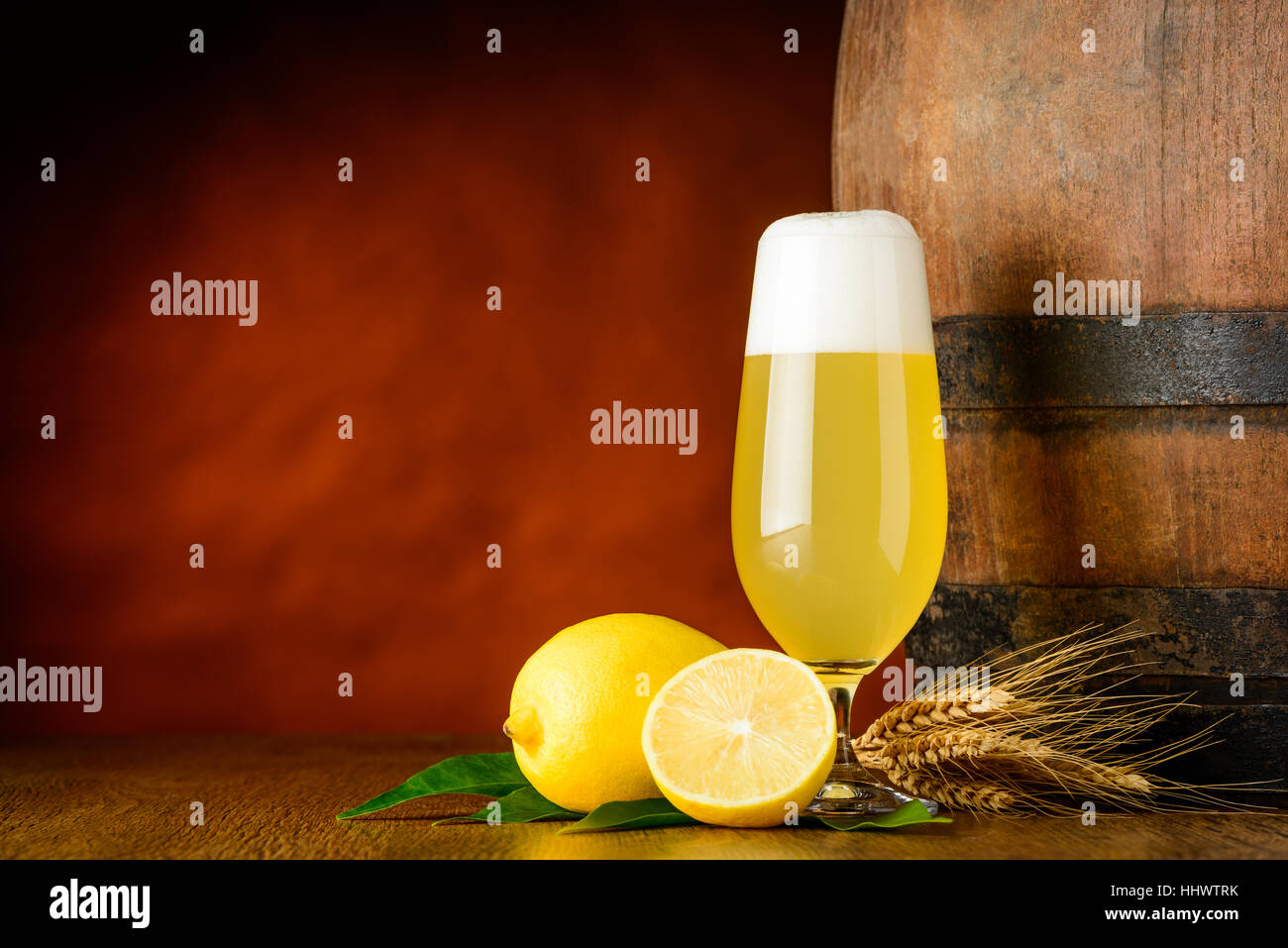 One glass of beer with lemon and wheat on rustic background in cellar ...