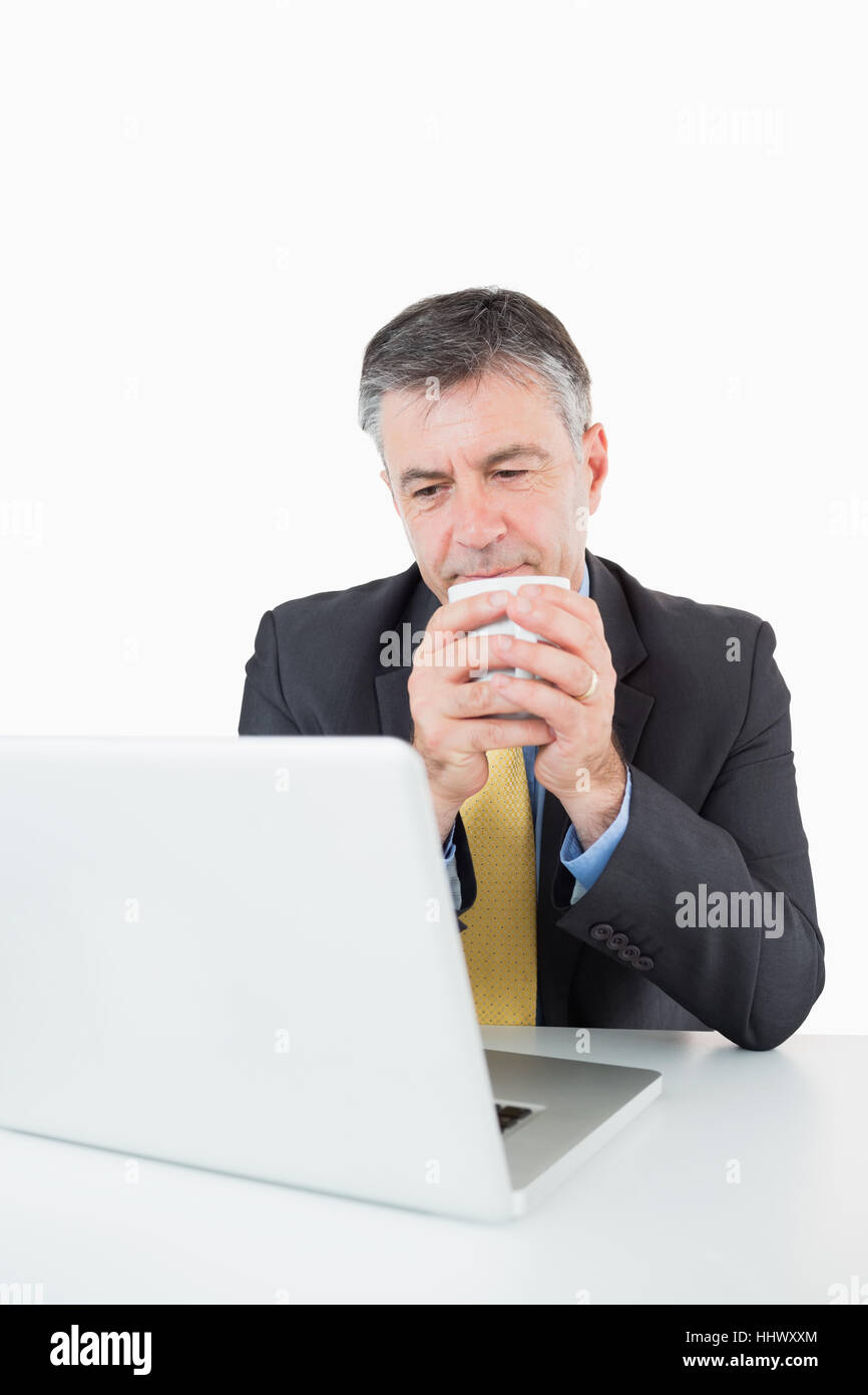 Man with a laptop is drinking coffee at his desk on a white background ...