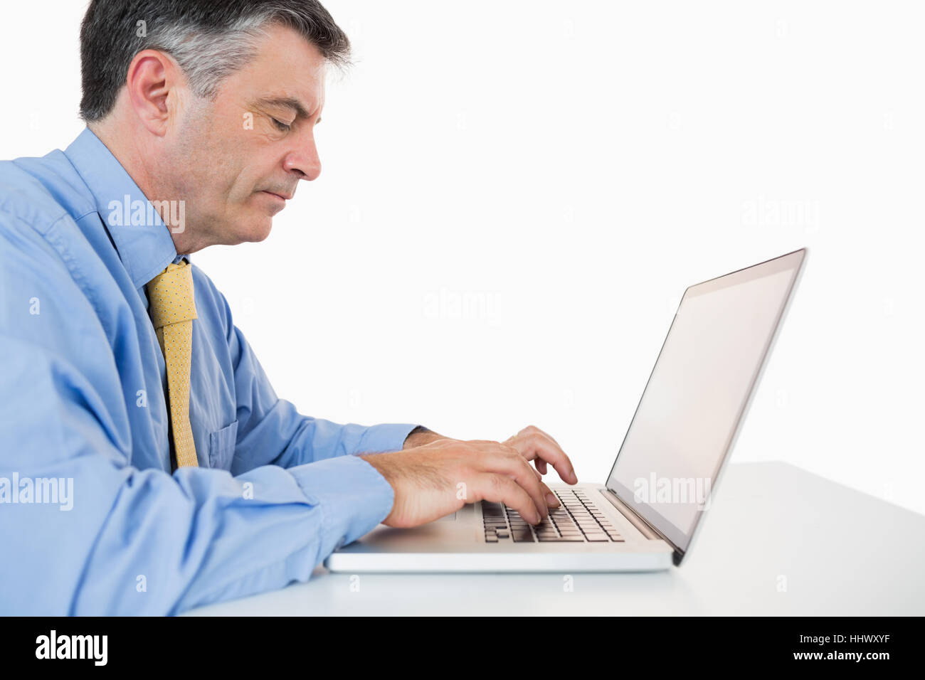 Concentrated man writing on laptop on his desk in a white background ...