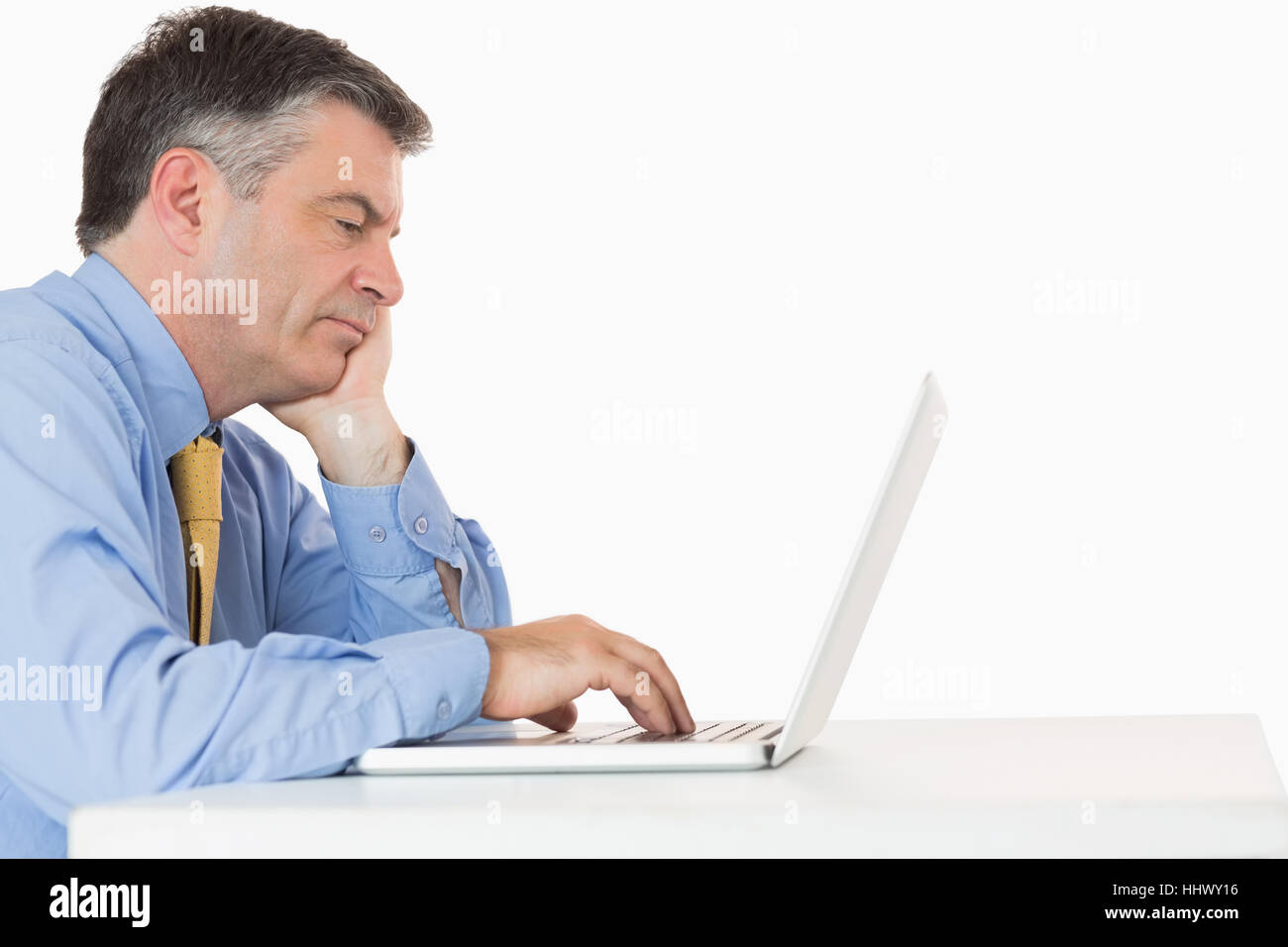 Tired man writing on his computer on his desk in a white background ...