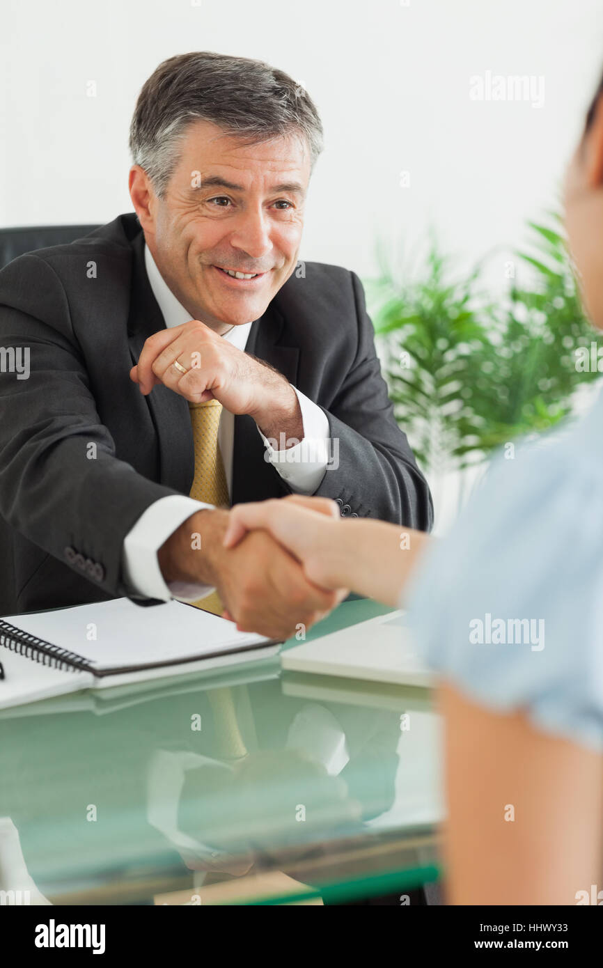 Smily businessman shaking a woman's hand in his office Stock Photo - Alamy
