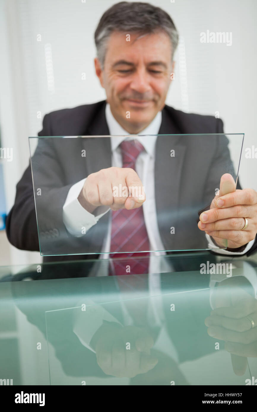 Smiling man touching on a virtual screen on his desk in his office ...