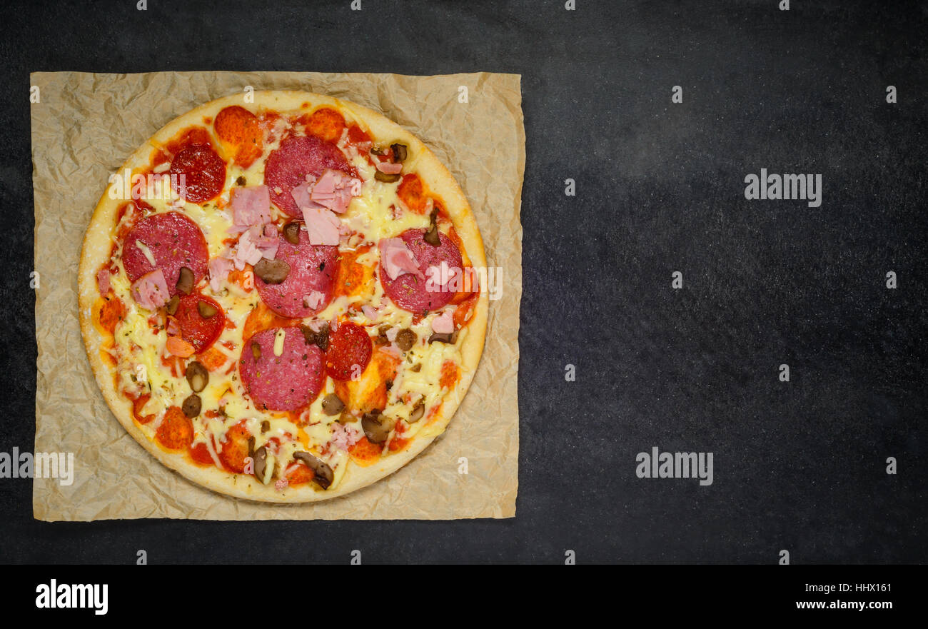 Junk Food Baked Pizza with Cheese and Salami on Dark Granite background ...