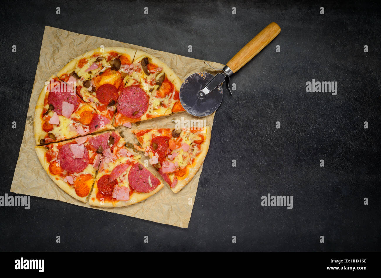 Sliced Junk Food Pizza sliced with a pizza-slicer. Salami and Cheese on ...